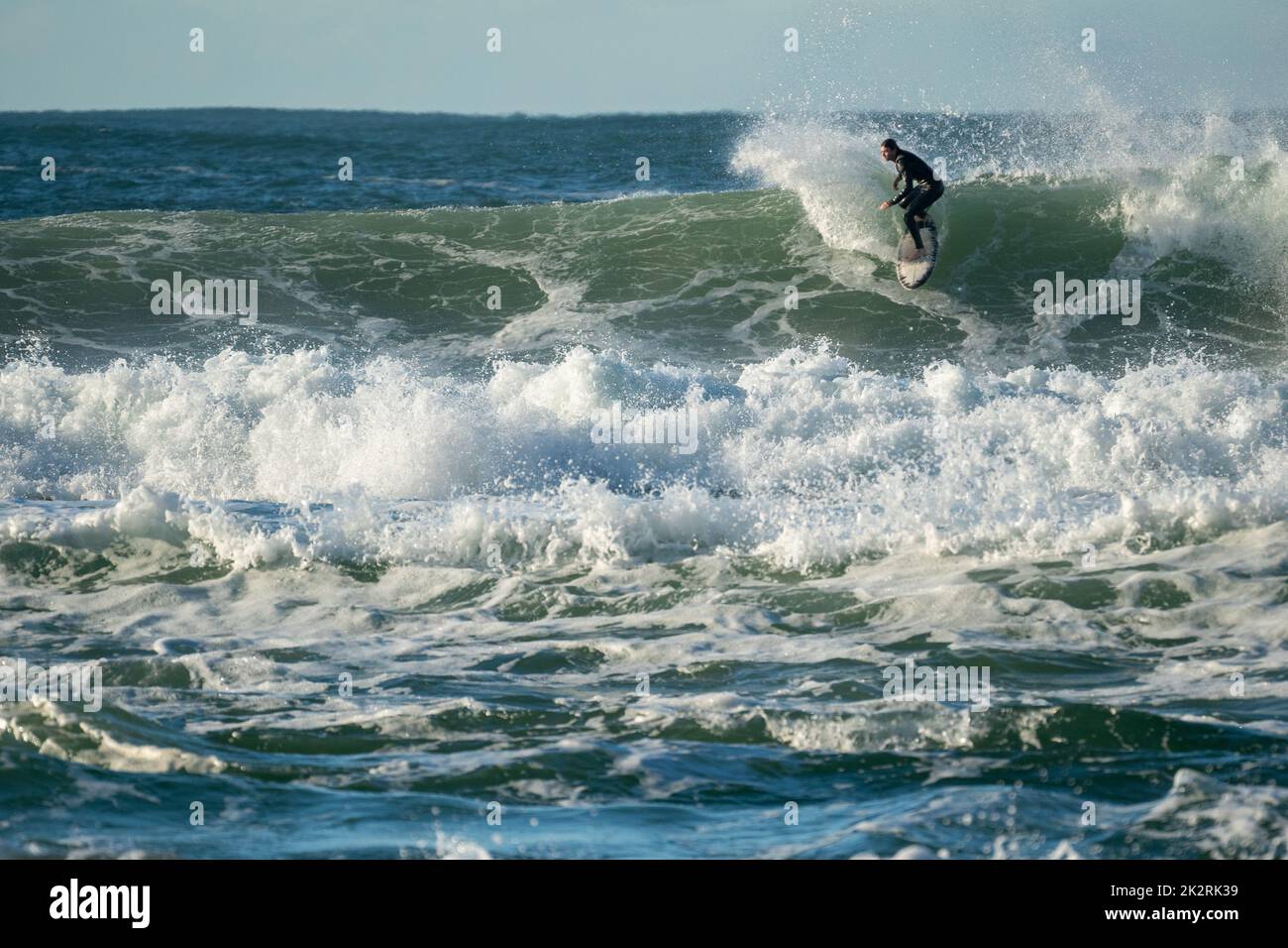 A young surfer catching waves before work on an early Friday morning at ...