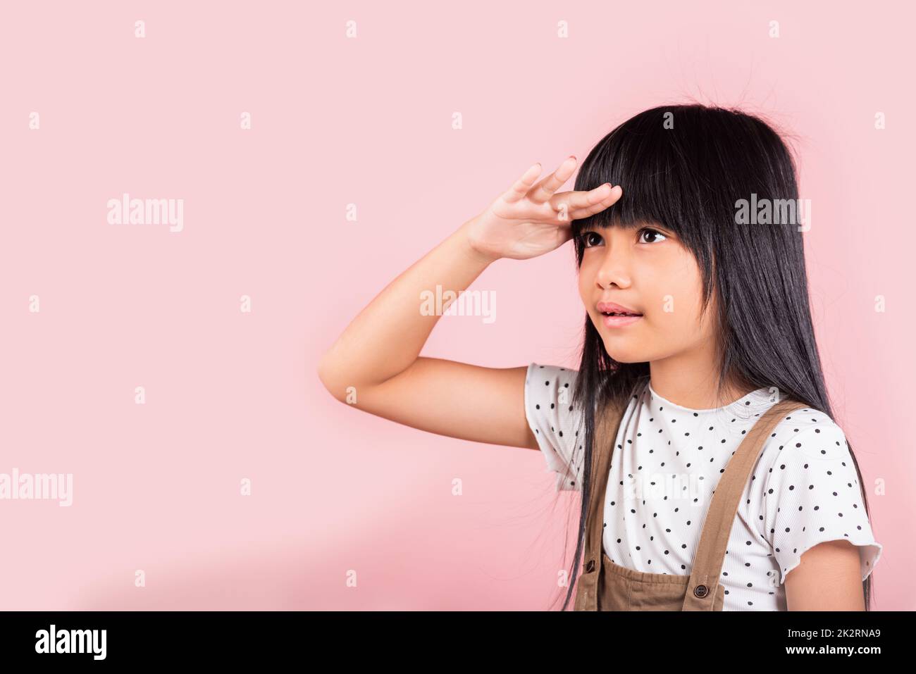 Asian little kid 10 years old looking far away with hand over head ...