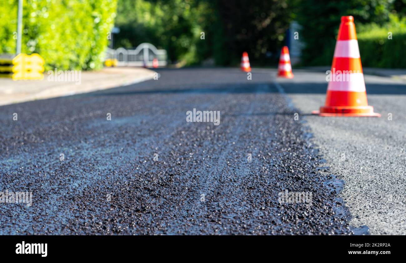 Construction cones marking part of road with a layer of fresh asphalt ...
