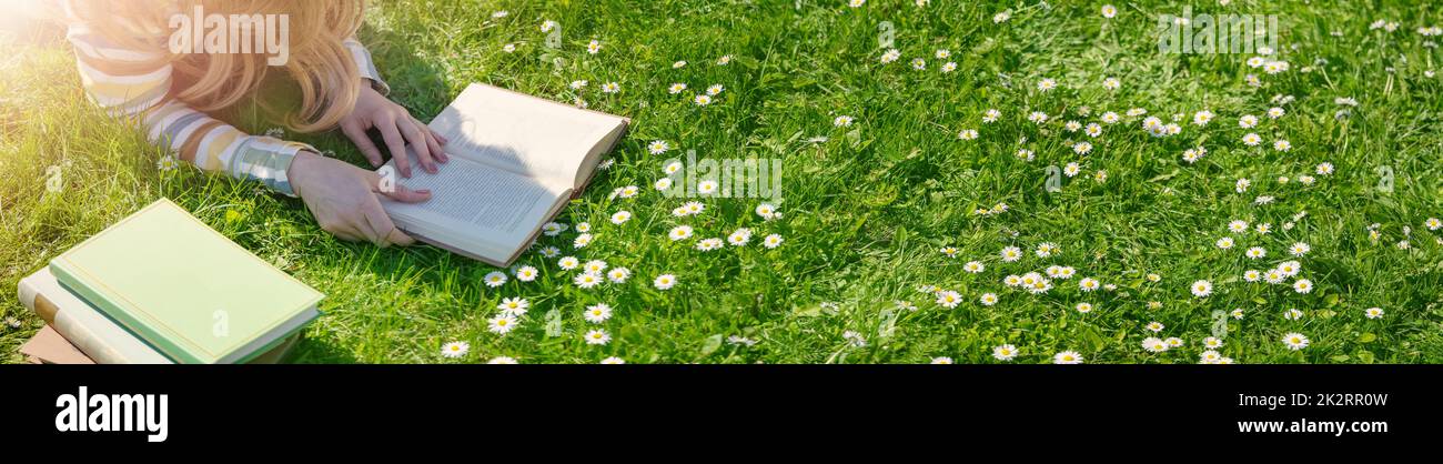 Young woman lying on the field and reading some books Stock Photo - Alamy