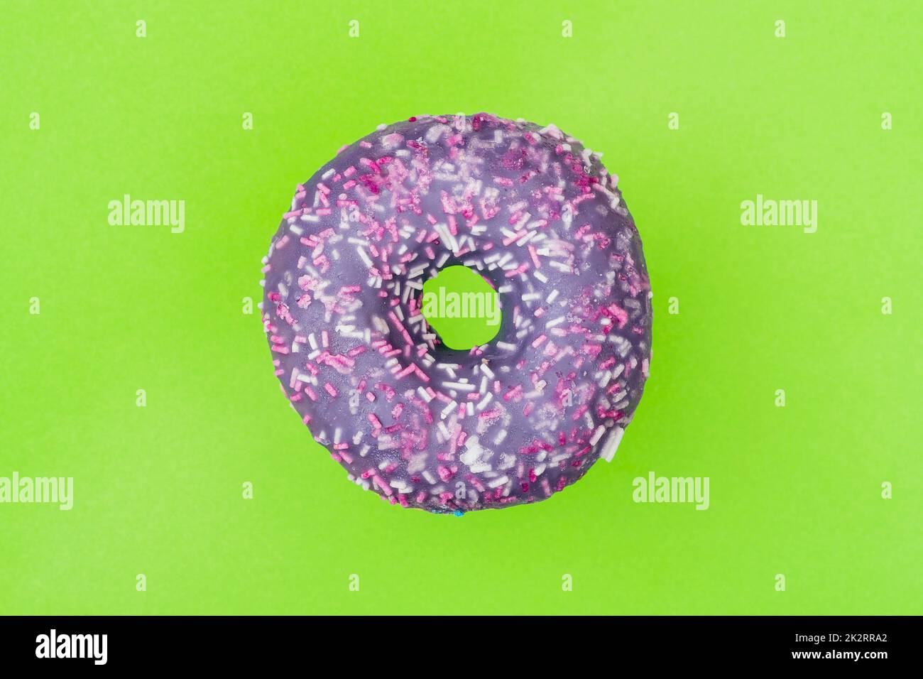 Purple glazed donut on a green background Stock Photo - Alamy