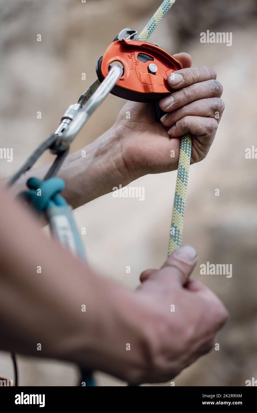 Man's hands operating a rock climbing belaying device Stock Photo - Alamy