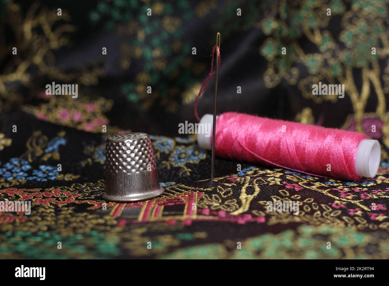 Pink Thread and Thimble on Vintage Chinese Black Silk Stock Photo - Alamy