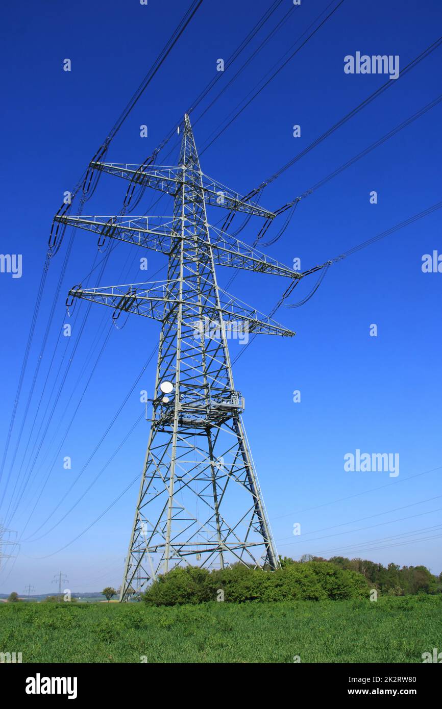 Single high voltage pylon against a blue sky Stock Photo - Alamy