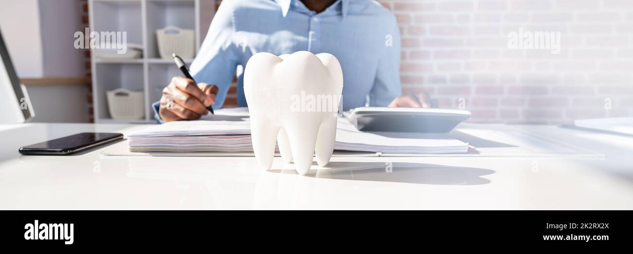 Tooth In Front Of Businessperson Calculating Bill Stock Photo - Alamy