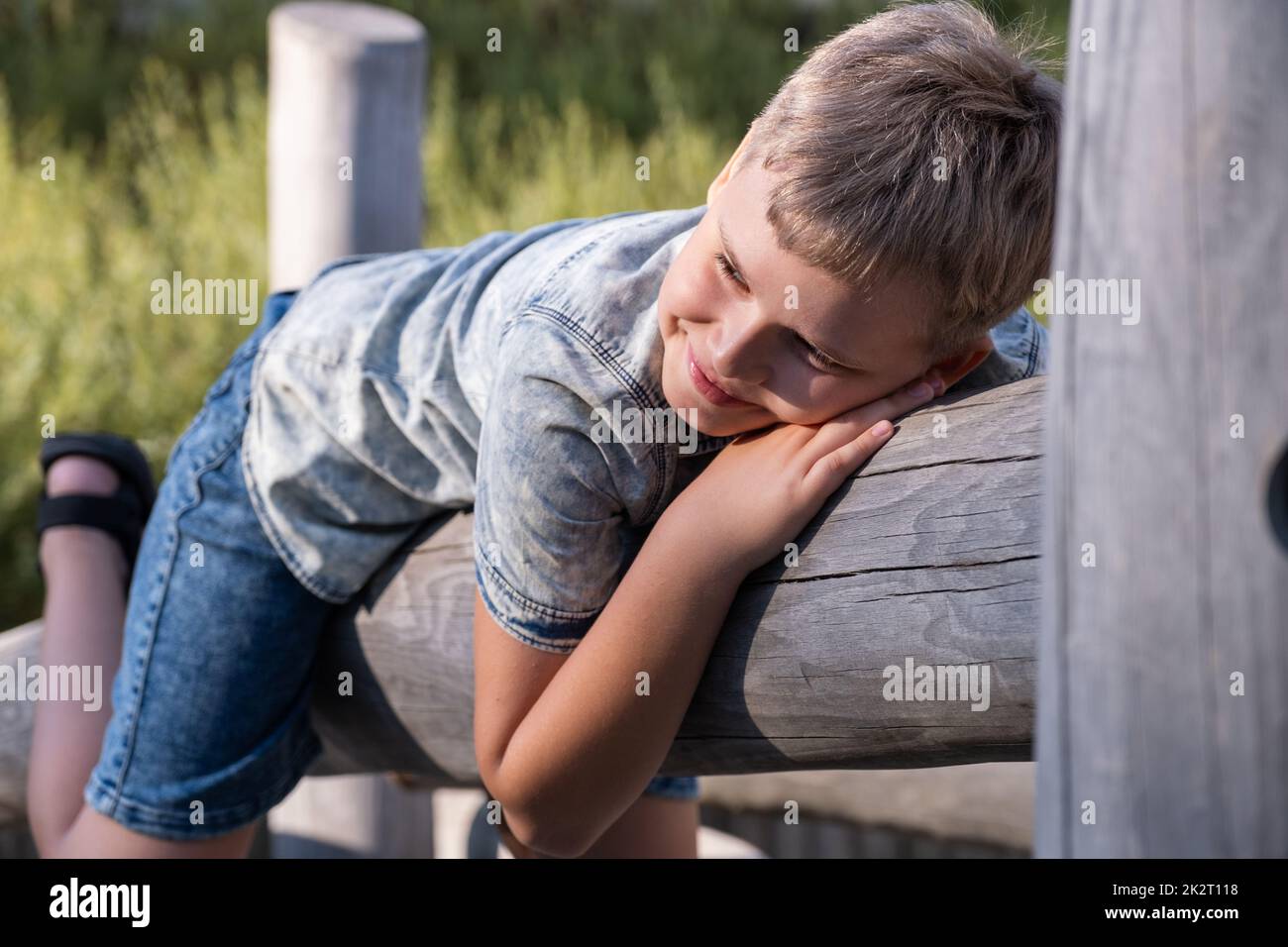 Cheerful and mischievous boy having fun at wooden playground outdoors ...