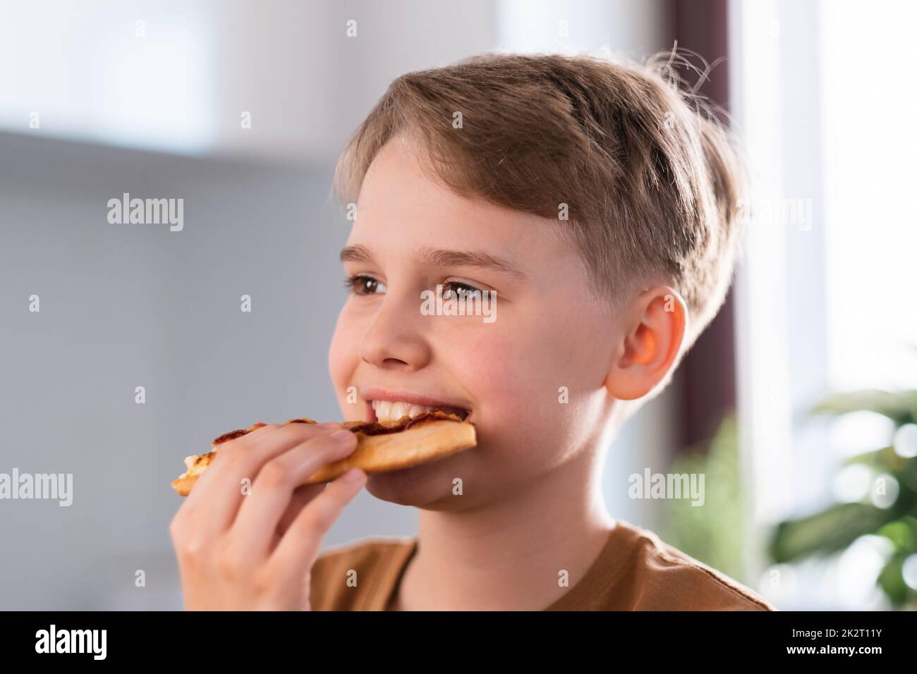 Happy teen boy enjoying eating delicious pizza at home. Portrait of a ...