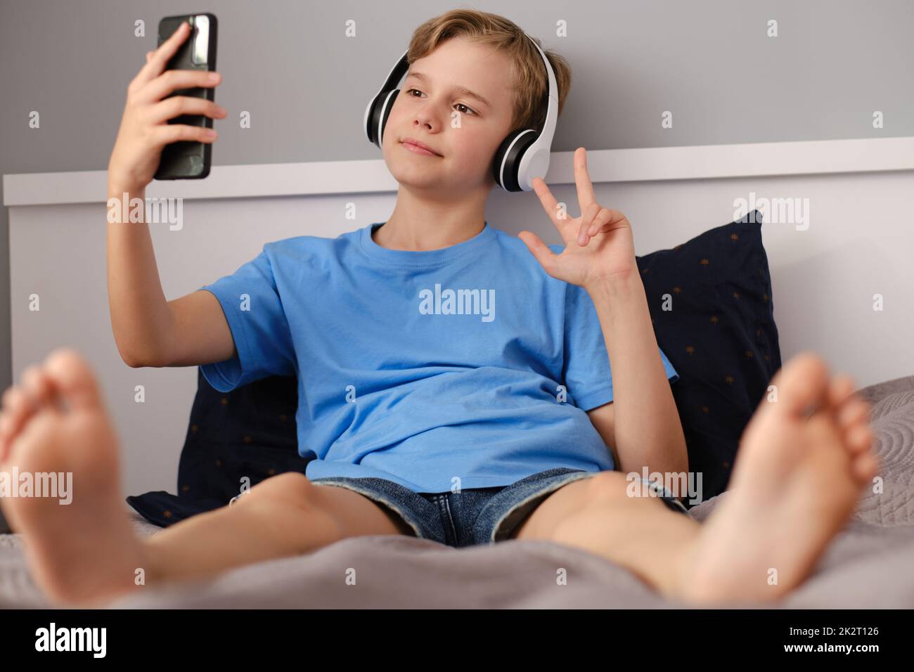 Teenage boy with smartphone communicates with peers and waves his hand ...