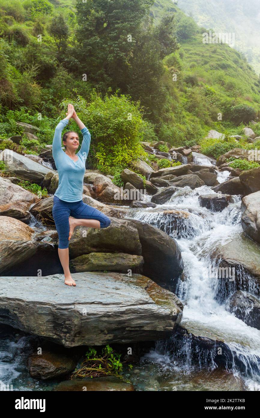 Woman in yoga asana Vrikshasana tree pose at waterfall outdoors Stock ...
