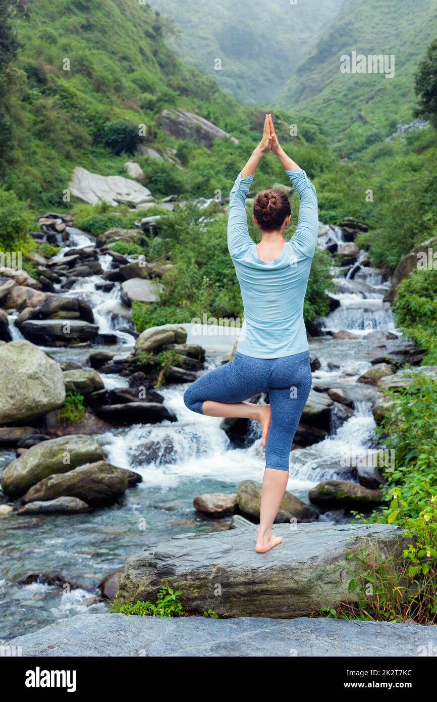 Woman in yoga asana Vrikshasana tree pose at waterfall outdoors Stock ...