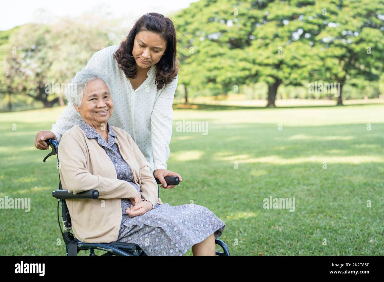 Caregiver help and care Asian senior or elderly old lady woman patient sitting on wheelchair in ...
