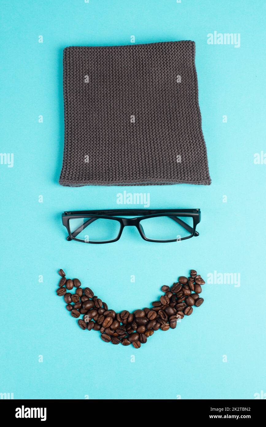 Human face made with a wool hat, glasses and coffee beans as a beard ...