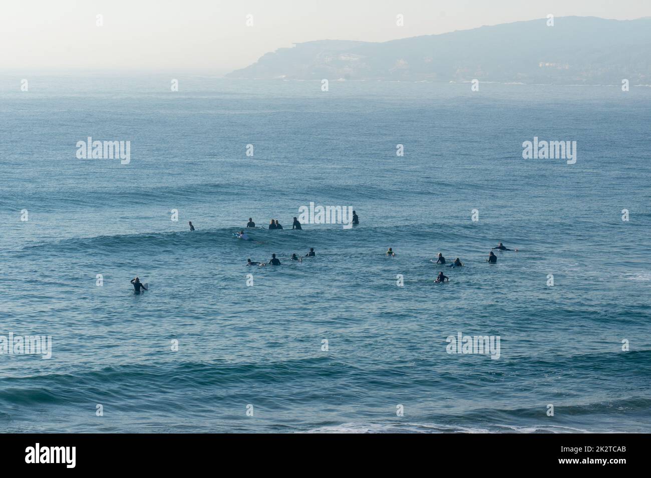 A beautiful view of a blue seascape with surfers catching waves in ...
