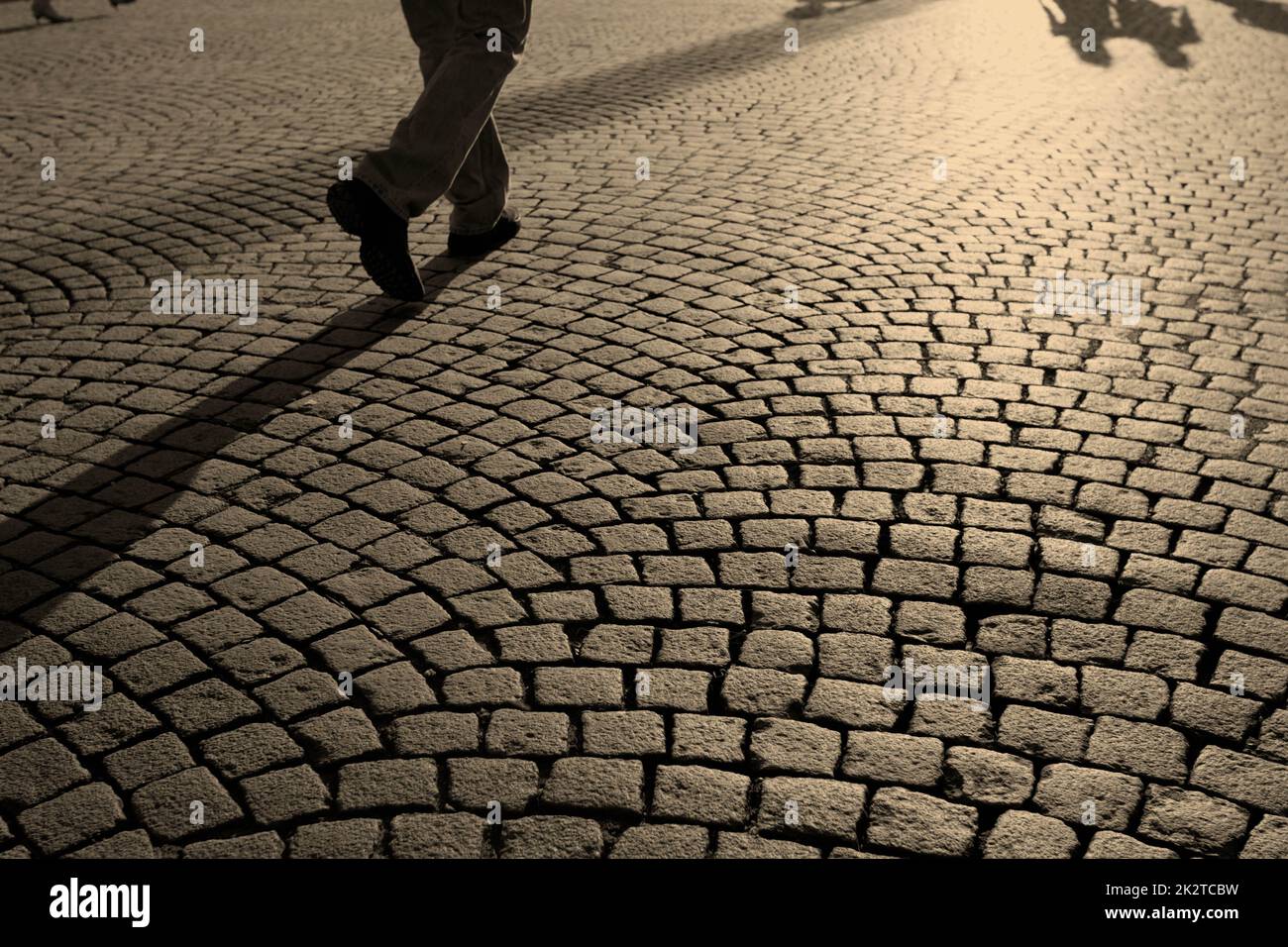 An old pavement ground and people walking there at the golden hour ...