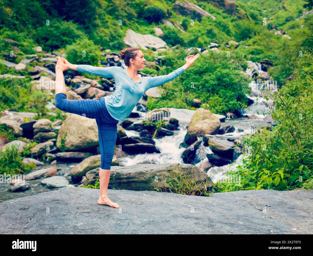 Woman doing yoga asana Natarajasana outdoors at waterfall Stock Photo ...