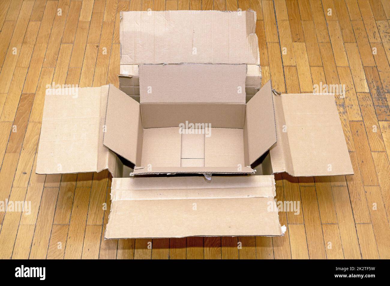Open cardboard boxes on wooden floor Stock Photo - Alamy