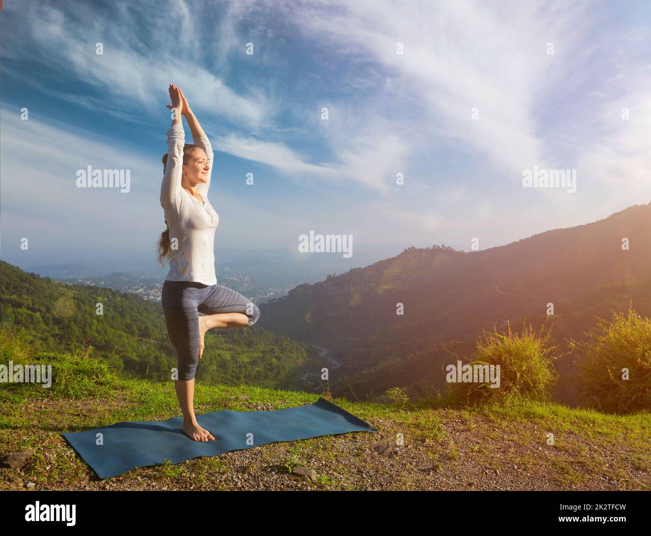 Woman in yoga asana Vrikshasana tree pose in mountains outdoors Stock ...
