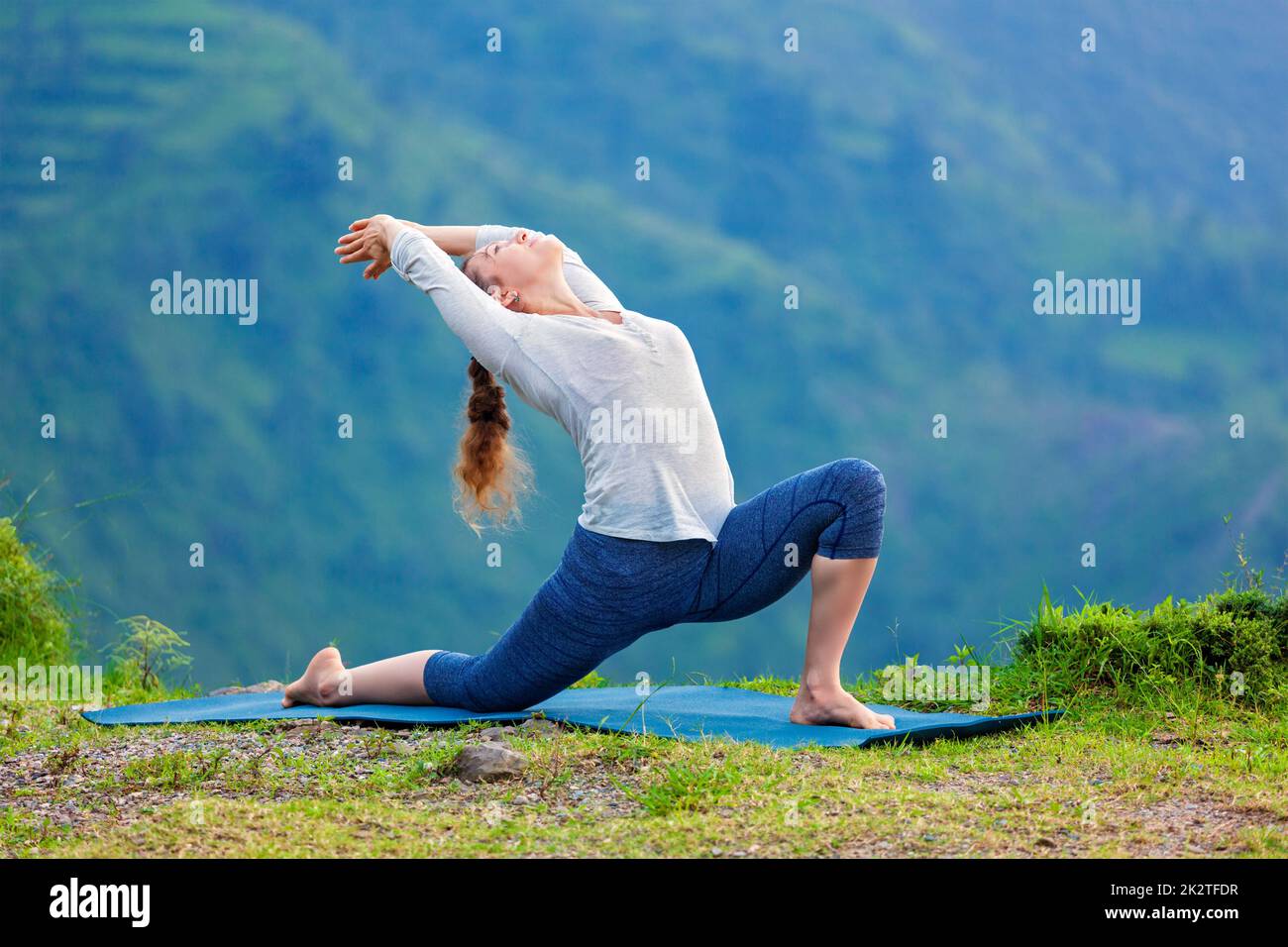 Sporty fit woman practices yoga asana Anjaneyasana in mountains Stock ...