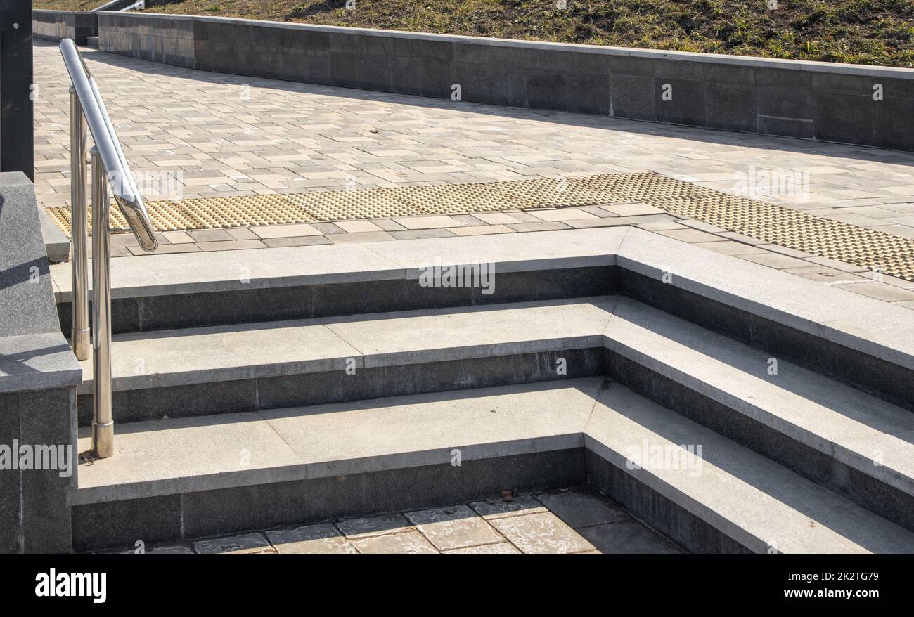 Close-up of granite stone steps located at an angle, in a metal railing ...