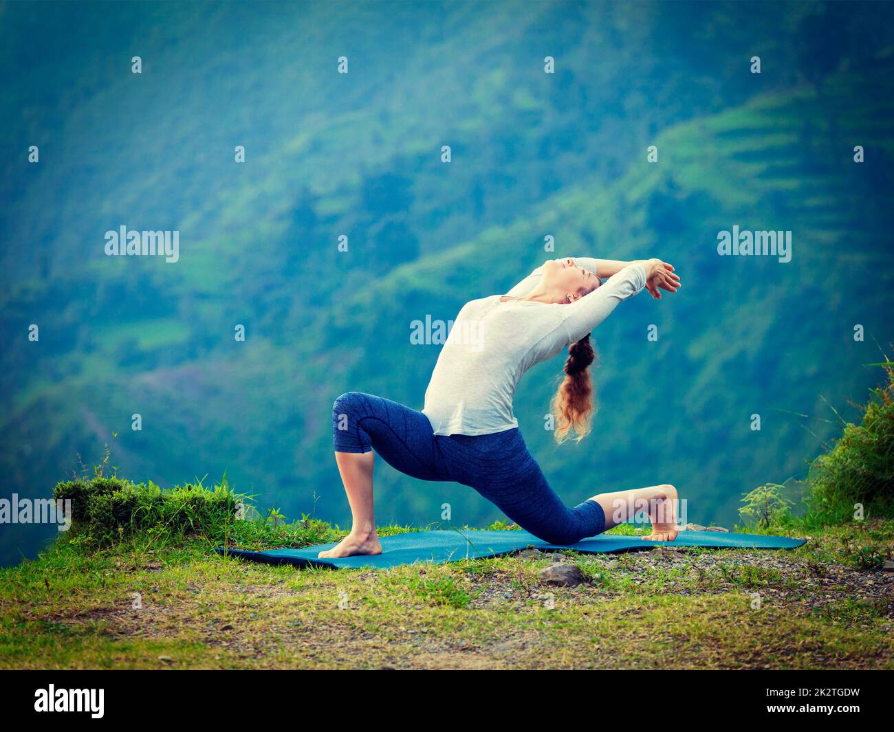 Sporty fit woman practices yoga asana Anjaneyasana in mountains Stock ...