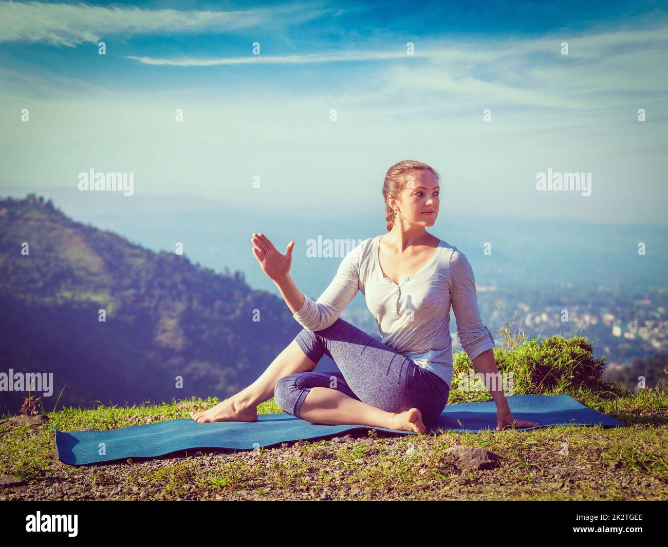 Woman doing Ardha matsyendrasana asana outdoors Stock Photo - Alamy
