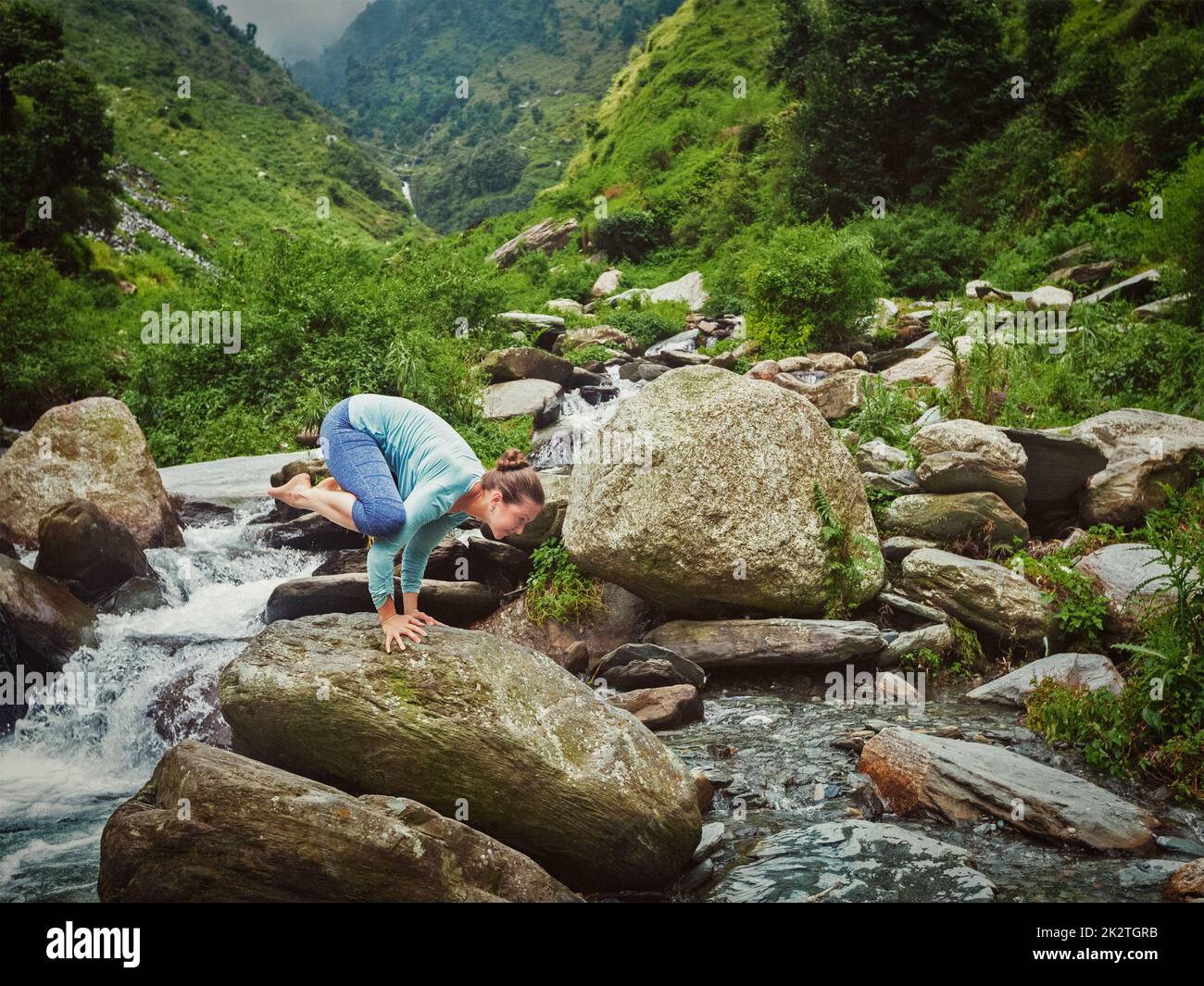 Woman doing Kakasana asana arm balance at waterfall Stock Photo - Alamy