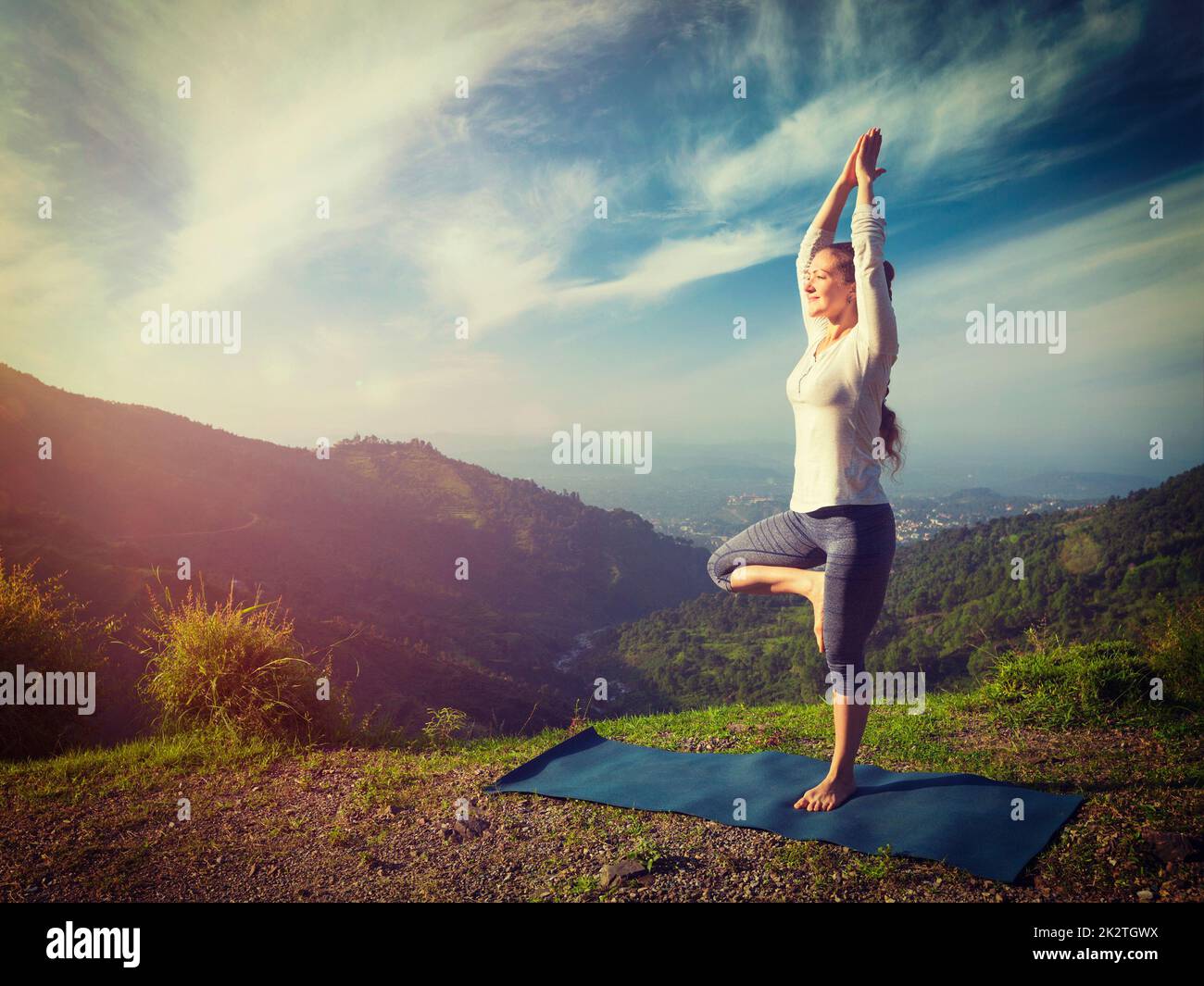 Woman in yoga asana Vrikshasana tree pose in mountains outdoors Stock ...