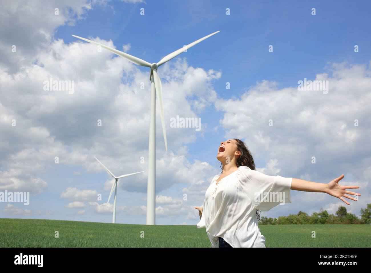 Happy woman outstretching arms in a wind farm Stock Photo - Alamy