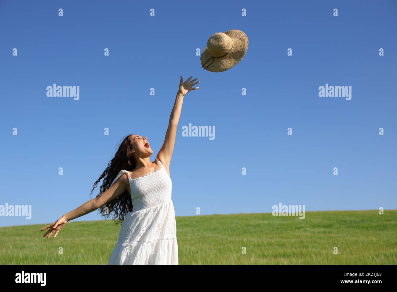 Happy woman throwing pamela hat to the air in a field Stock Photo - Alamy