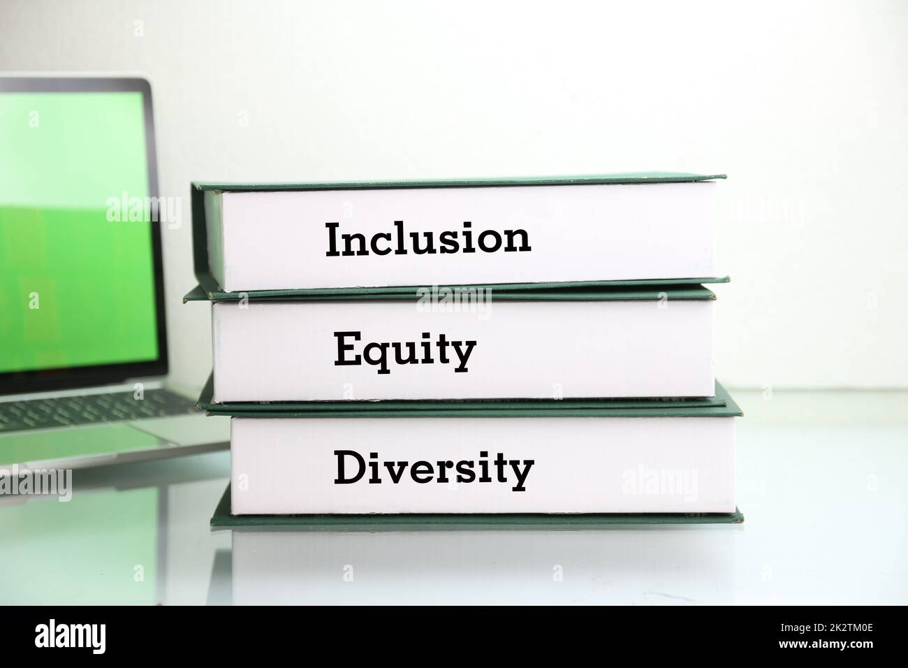 Books with words DEI, diversity, equity, inclusion on table with white ...