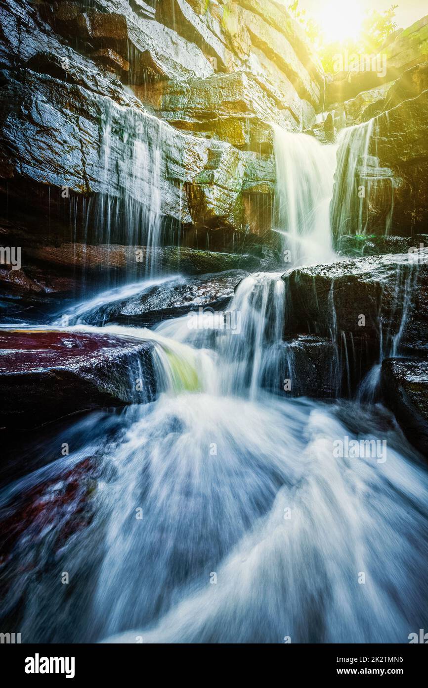 Tropical waterfall with sun rays Stock Photo - Alamy