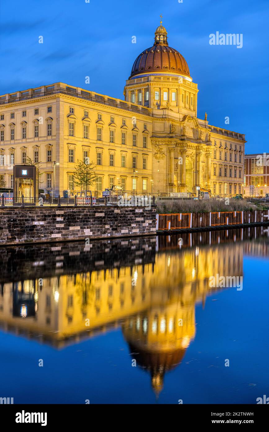 The beautiful reconstructed City Palace in Berlin at night reflected in ...