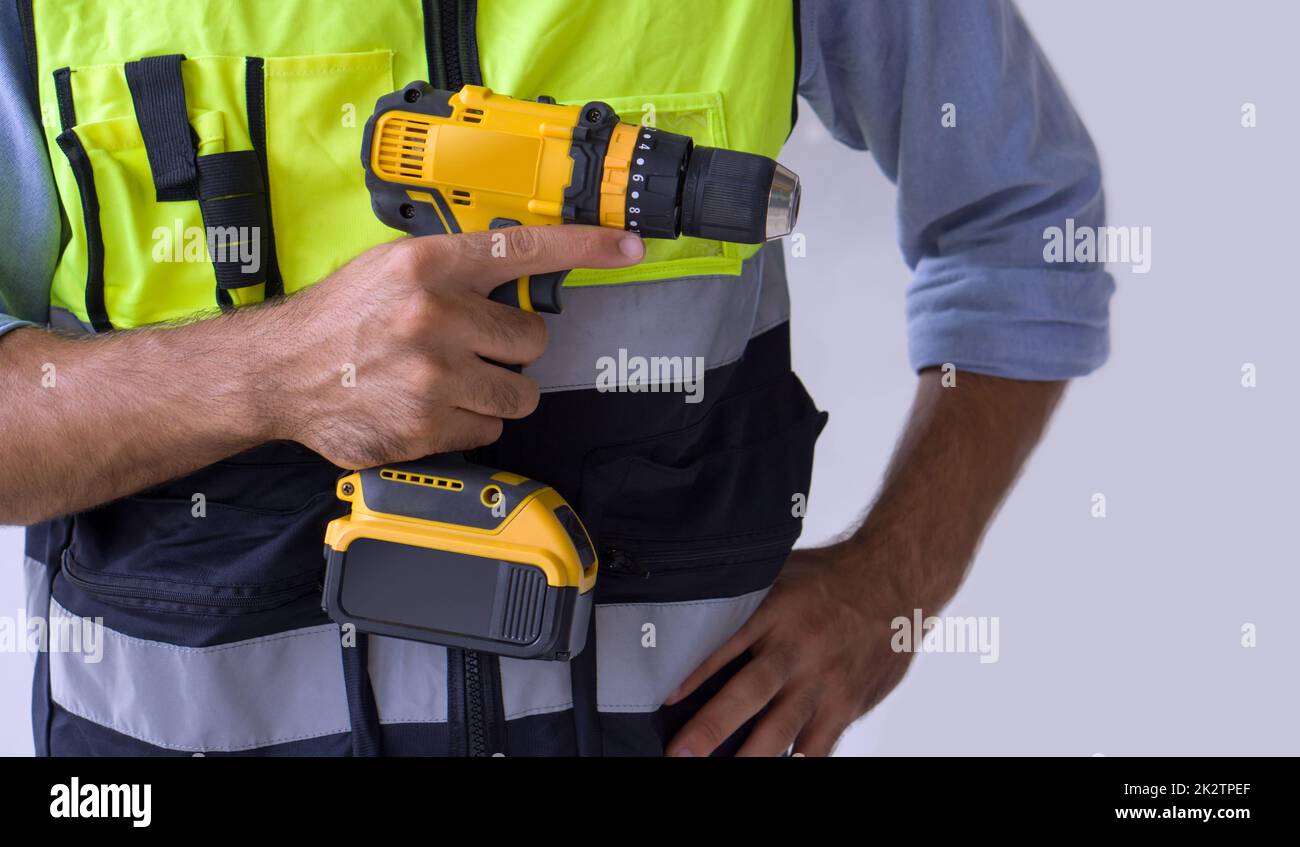 A yellow cordless electric drill with battery in the hand of a ...