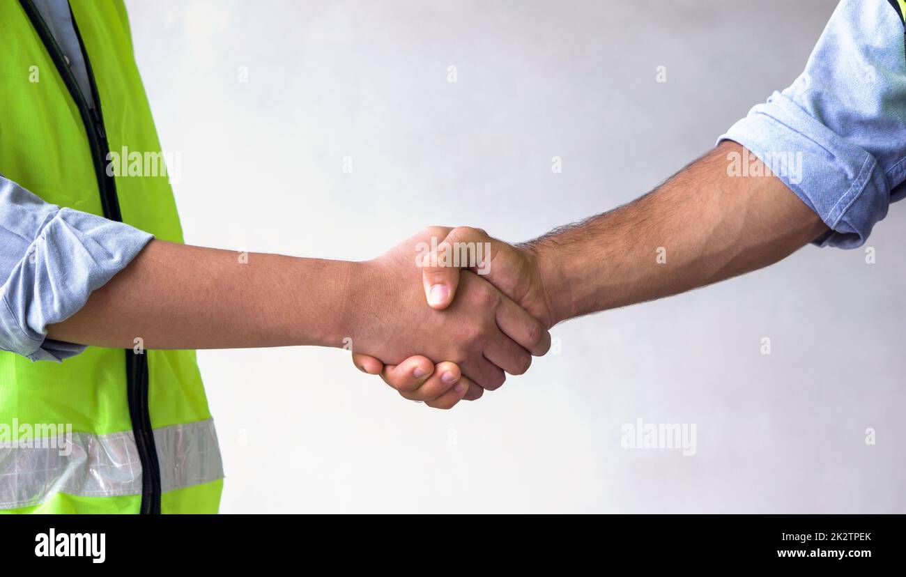 Closeup hand shaking in front of gray plaster wall. Both ware blue ...