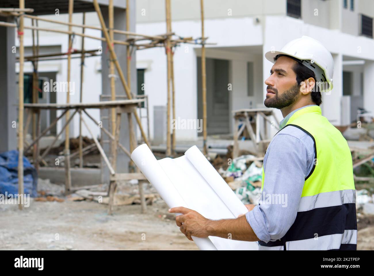 Young engineer in a construction helmet and safety vest holding a floor ...