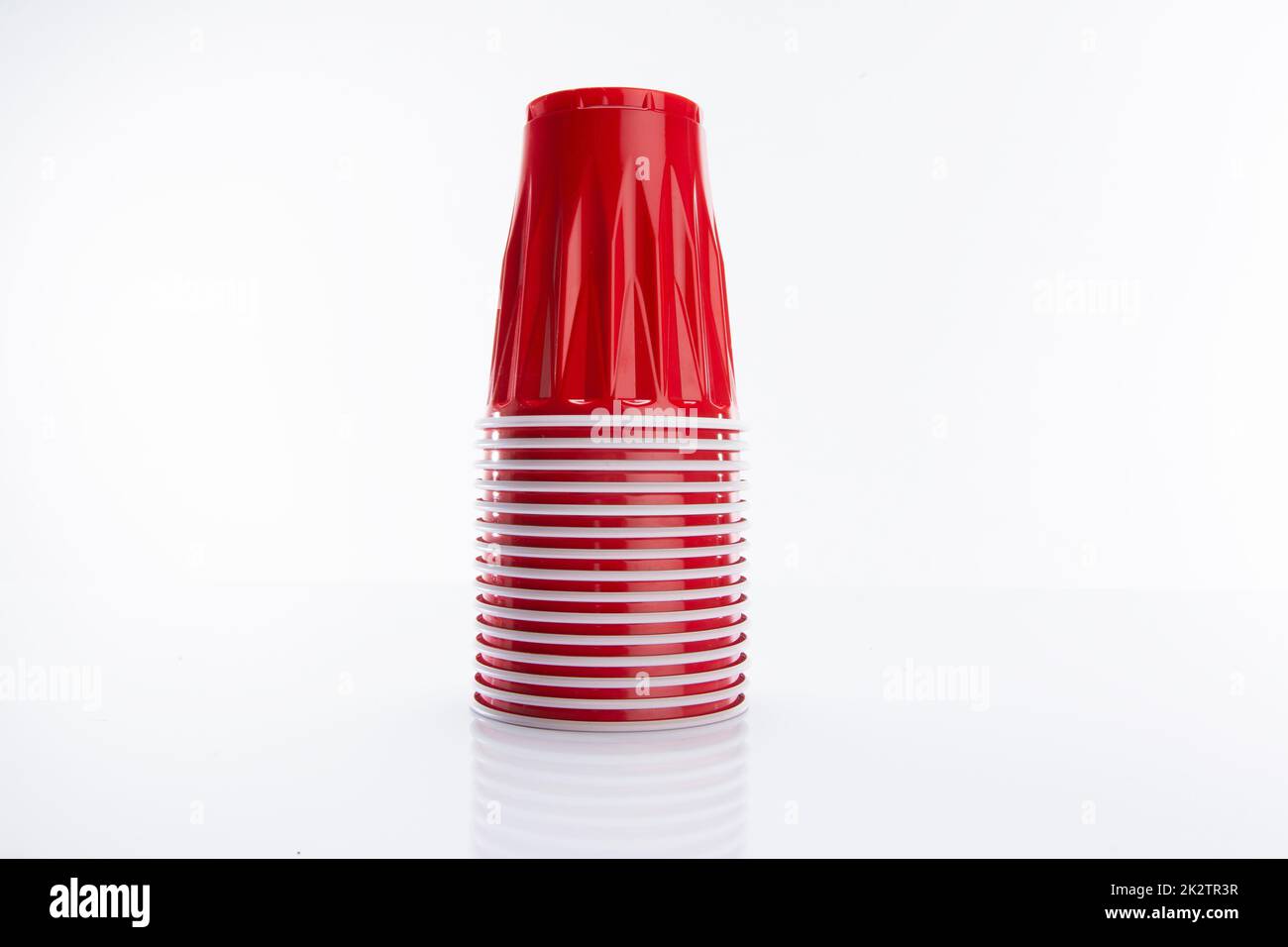 A horizontal stack of disposable red plastic cups isolated on a white ...