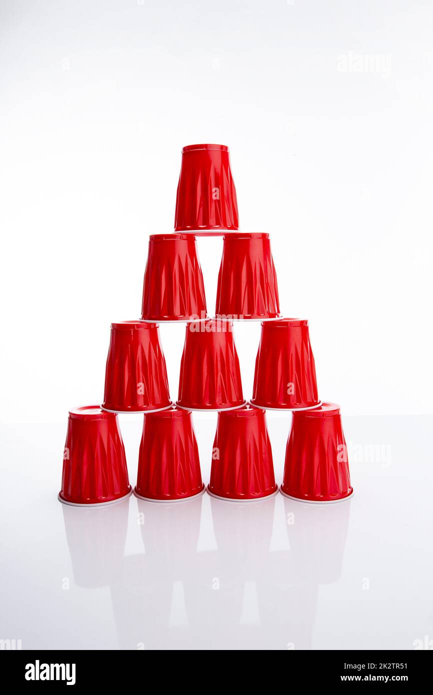 A vertical of a cup pyramid made of red disposable plastic cups against a white background Stock ...