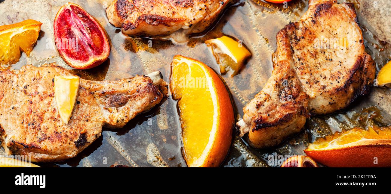 Pork steak on the bone baked with citrus fruits Stock Photo - Alamy