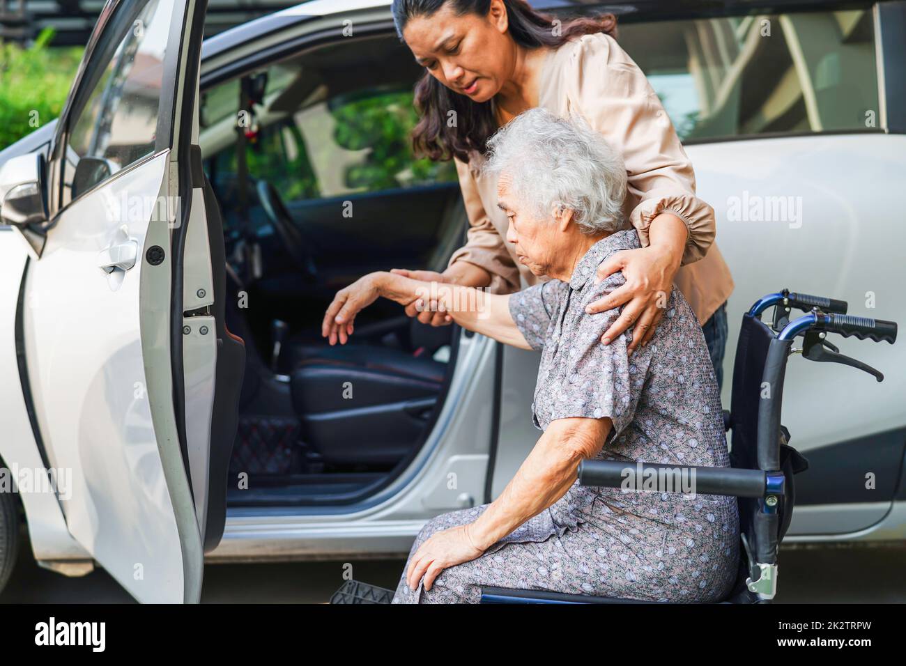 Caregiver help Asian elderly woman disability patient get in her car, medical concept Stock ...