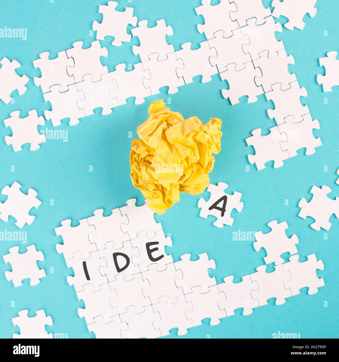 Puzzle on a blue background, yellow crumbled paper, word idea is ...