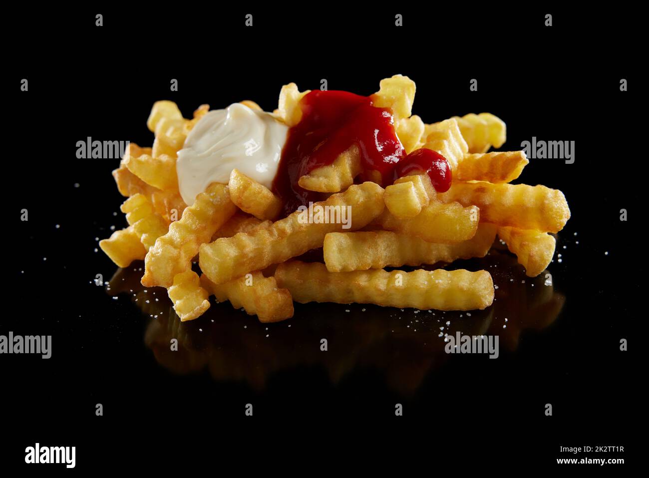 Delicious corrugated French fries with sauces against black background ...