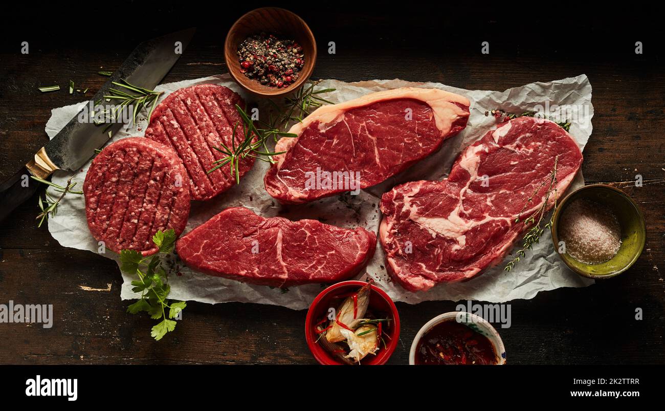 Raw burger cutlets and beef steaks with various condiments Stock Photo ...
