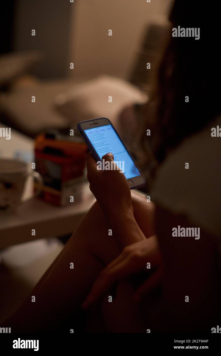 A girl scrolling through her phone on a couch Stock Photo - Alamy