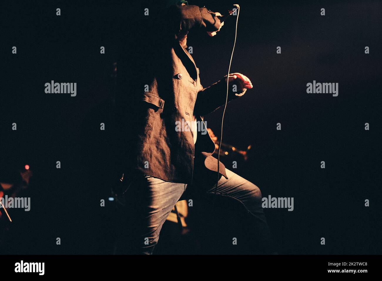A Caucasian male singer performing on the stage against a dark ...