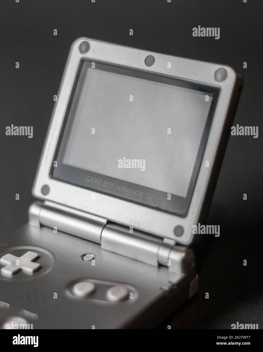 A vertical shot of a vintage gray Game Boy Advance SP on a dark surface ...