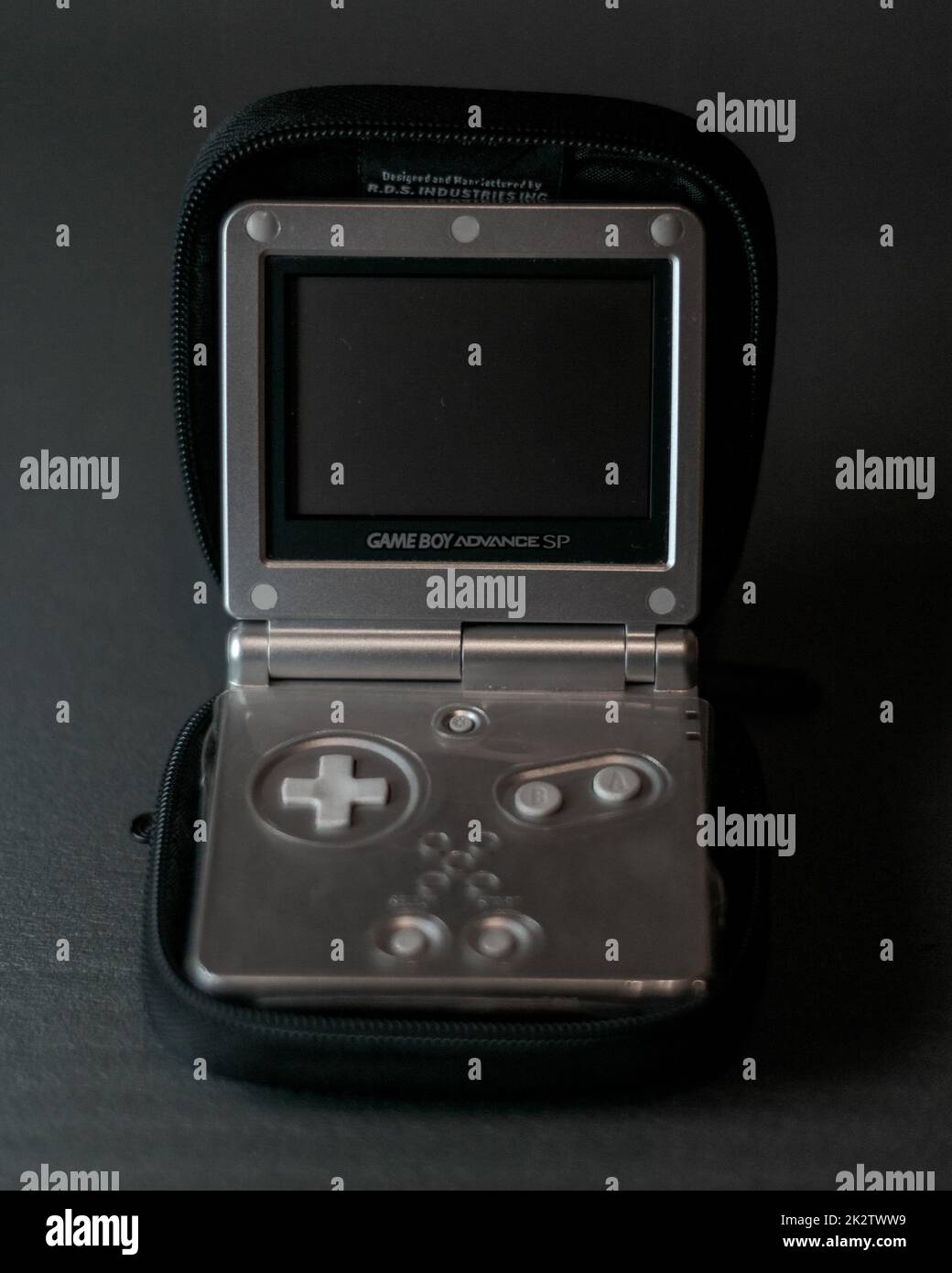 A vertical shot of a vintage gray Game Boy Advance SP with a case on a ...