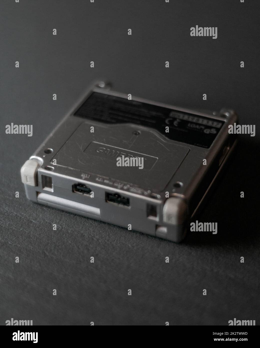 A vertical shot of a vintage gray Game Boy Advance SP on a dark surface ...