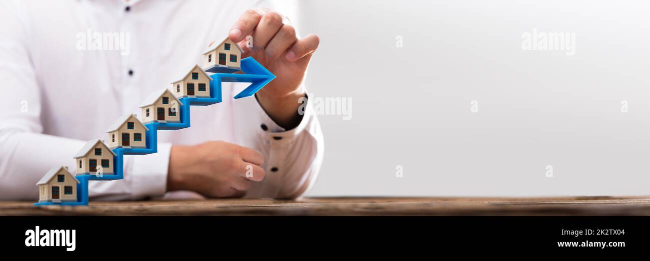 Businessman placing house models on increasing arrow staircase Stock ...