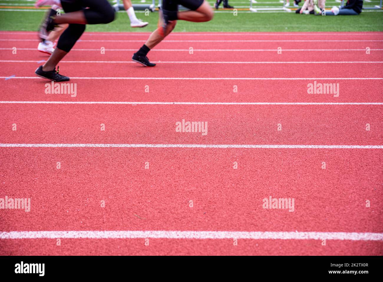 Two runners race on a red track and field athletic track with lane ... Two runners race on a red track and field athletic track with lane ...