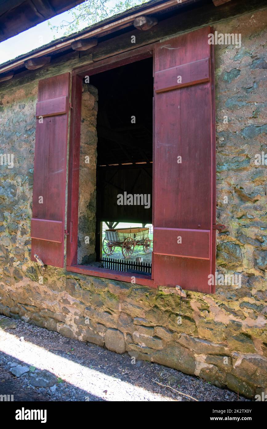 Colonial wagon seen through open stone barn window red shutters Stock ...